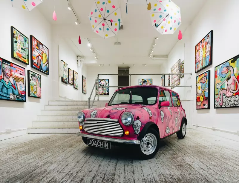 Seniman jalanan Joachim nyopir Mini Cooper sing ditutupi grafiti pink menyang galeri London