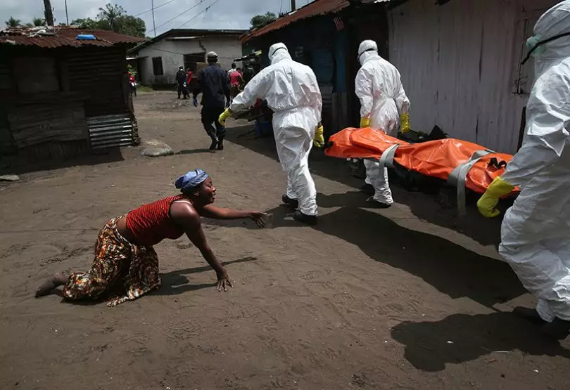 Bản quyền: John Moore / Getty Images. Một người phụ nữ bò về phía thi thể của em gái mình khi các thành viên đội mai táng Ebola đưa cô ấy đi.