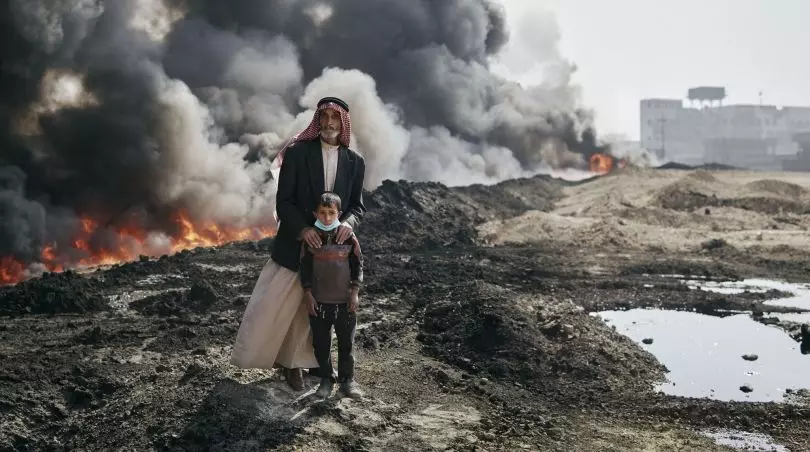 Kharim and his guardian, Nadak, beside a burning oil field. Qayyarah, Nineveh Governorate, Iraq, October 25, 2016. From [We Came From Fire ]( https://amzn.to/2L9l8Vm) by Joey L. – published by powerHouse Books