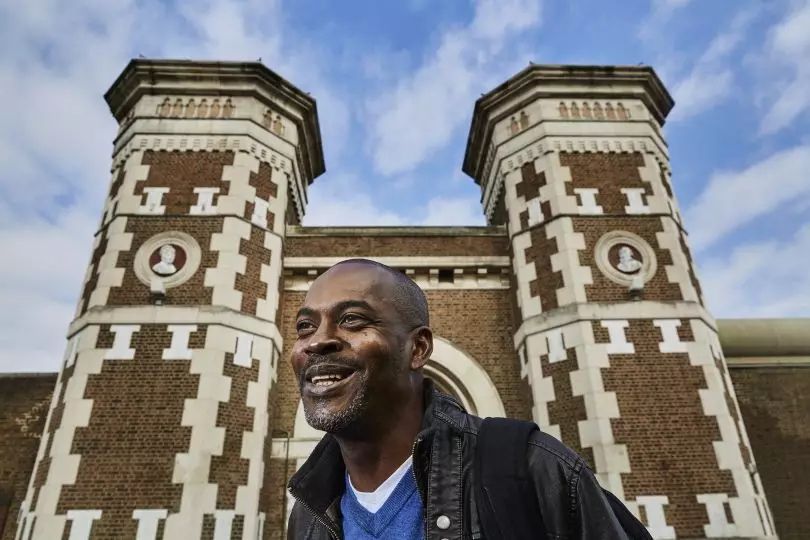 Stephen Akpabio-Klementowski, membro dello staff della Open University, laureato ed ex carcere che ha studiato per la sua laurea durante una condanna a 16 anni, nella foto qui fuori dalla prigione di Wormwood Scrubs, è presente nella nuova collezione di The OU del famoso fotografo Chris Floyd, pubblicata oggi in occasione del 50° anniversario