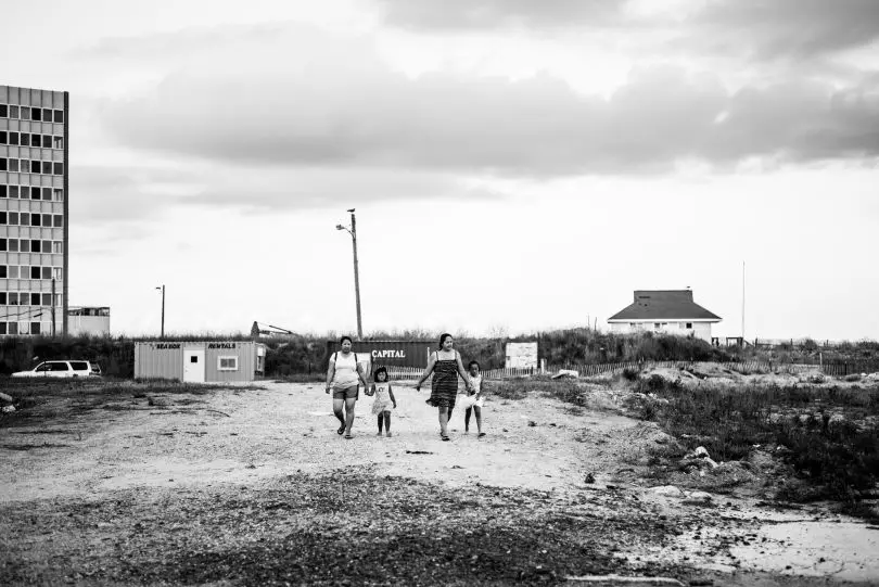 Mães e filhas caminham entre os detritos do desenvolvimento fracassado. © Timothy Roberts