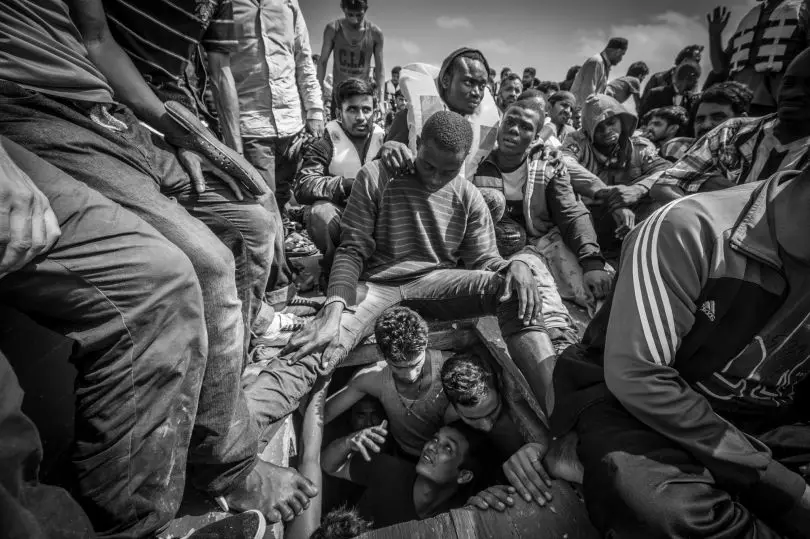 A bord d'un vaixell de pesca a 30 milles de la costa de Líbia, un home de Bangla Desh demana que l'alliberin de l'amuntegament bodega del vaixell on estava ple de 150 homes en condicions semblants a l'esclavitud. El vaixell transportava 414 migrants i refugiats que intentaven arribar a Itàlia. El vaixell de migrants va ser interceptat pel vaixell de rescat de l'ONG Migrant Offshore Aid Station, i totes les persones a bord van ser evacuades. © Jason Florio. Guanyador de la sèrie de fotoperiodisme, premis de fotografia Magnum i LensCulture 2017