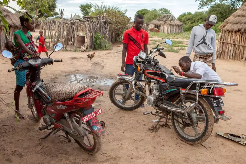 Unos chicos reparando sus motos frente a su “Kimbo” donde viven, al sur de Angola