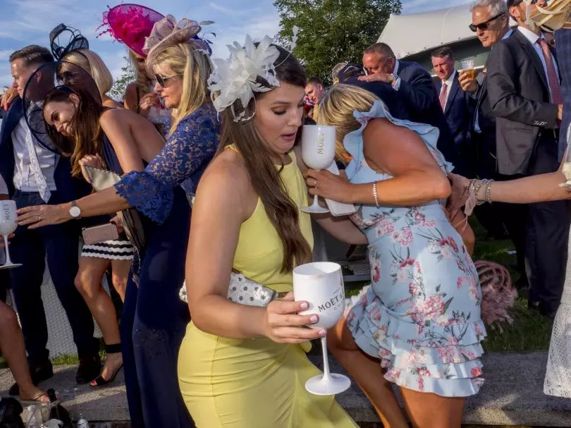 Tävlingsbesökare fortsätter att dricka på efterfesten på Ladies Day på Epsom. Juni 2018 © Peter Dench